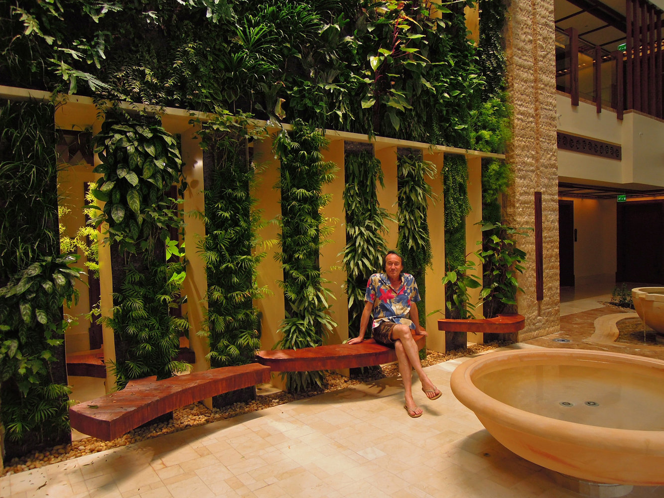 Patrick Blanc sitting on a wooden bench in front of the Beach Suites ...